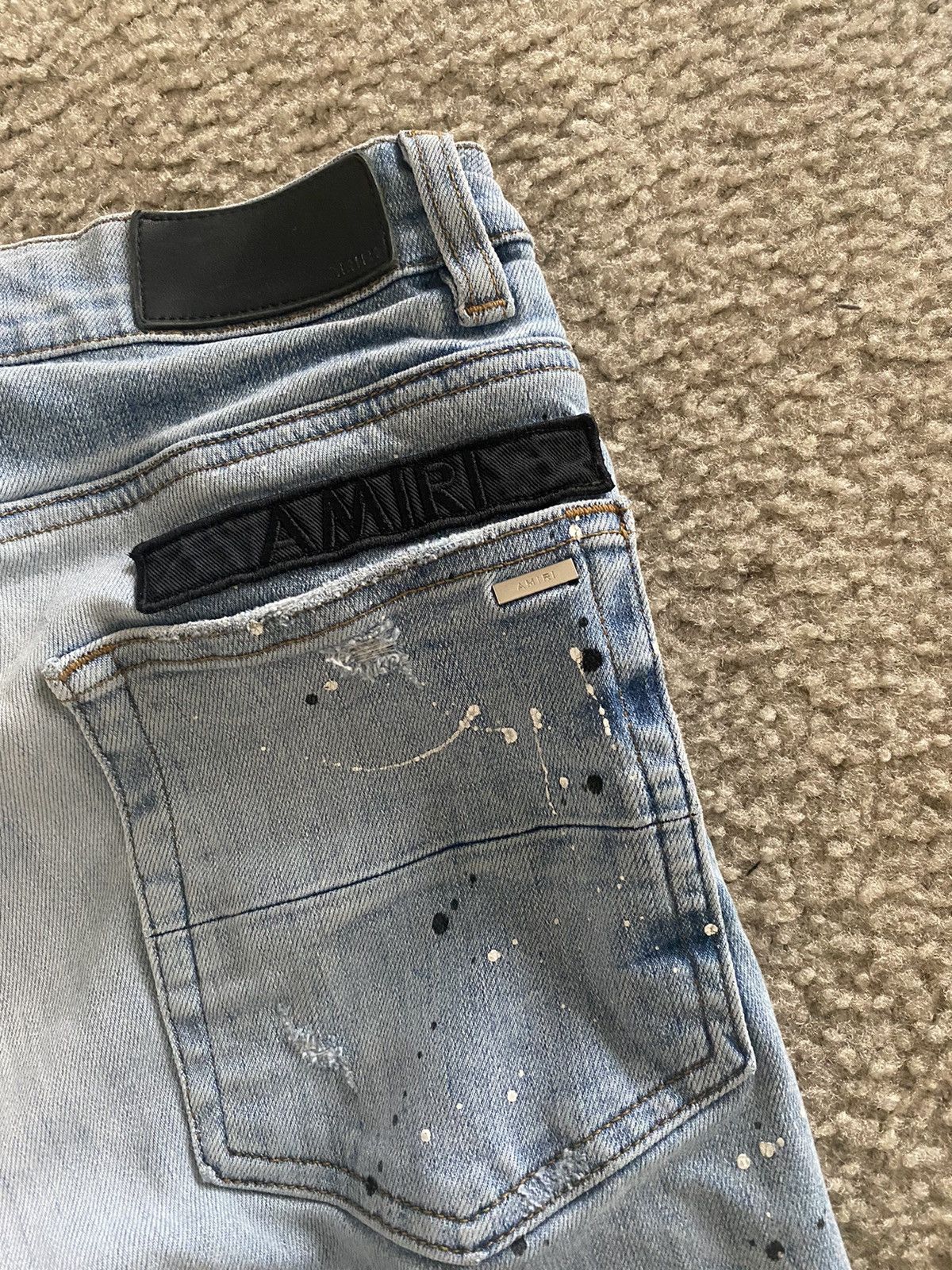 Amiri Light wash with paint specs and black patches | Grailed
